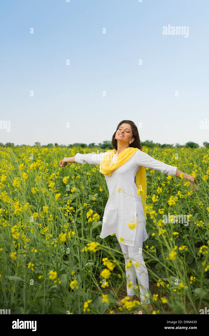 Woman standing in a mustard field and smiling Stock Photo - Alamy