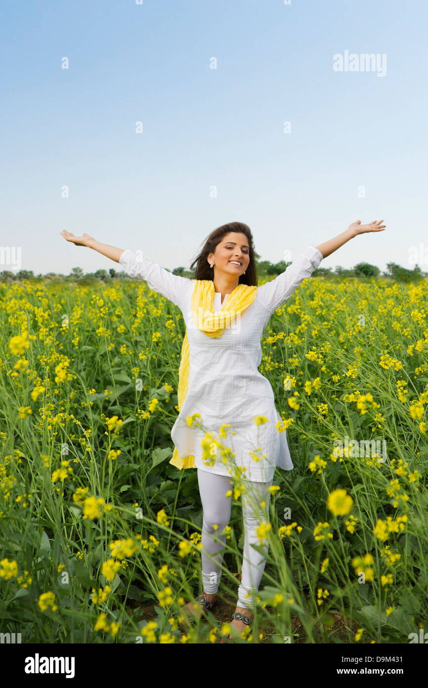 Woman standing in a mustard field and smiling Stock Photo - Alamy
