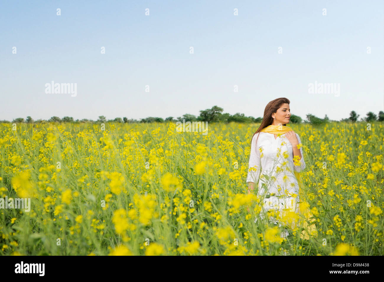 Woman standing in a mustard field and smiling Stock Photo - Alamy
