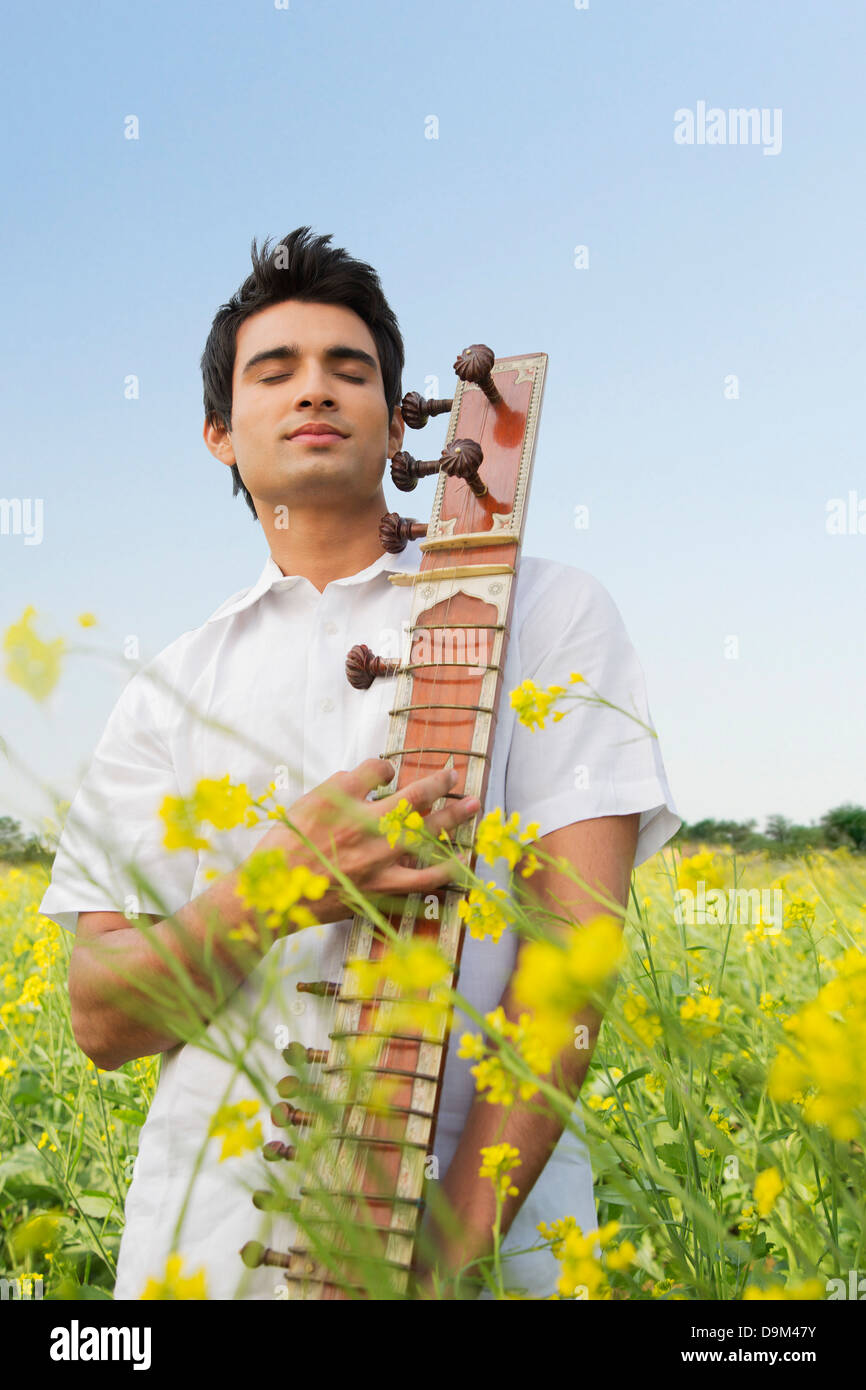 Man playing a sitar in a mustard field Stock Photo - Alamy