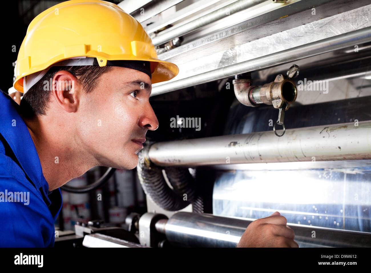industrial machine operator checking on machine while it's running ...