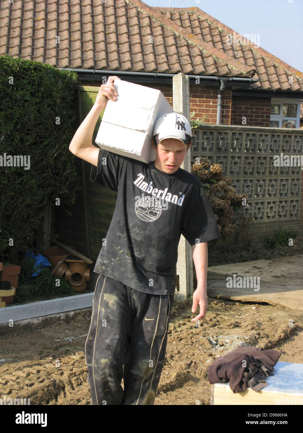 Apprentice builder / construction worker carrying thermalite bricks for ...