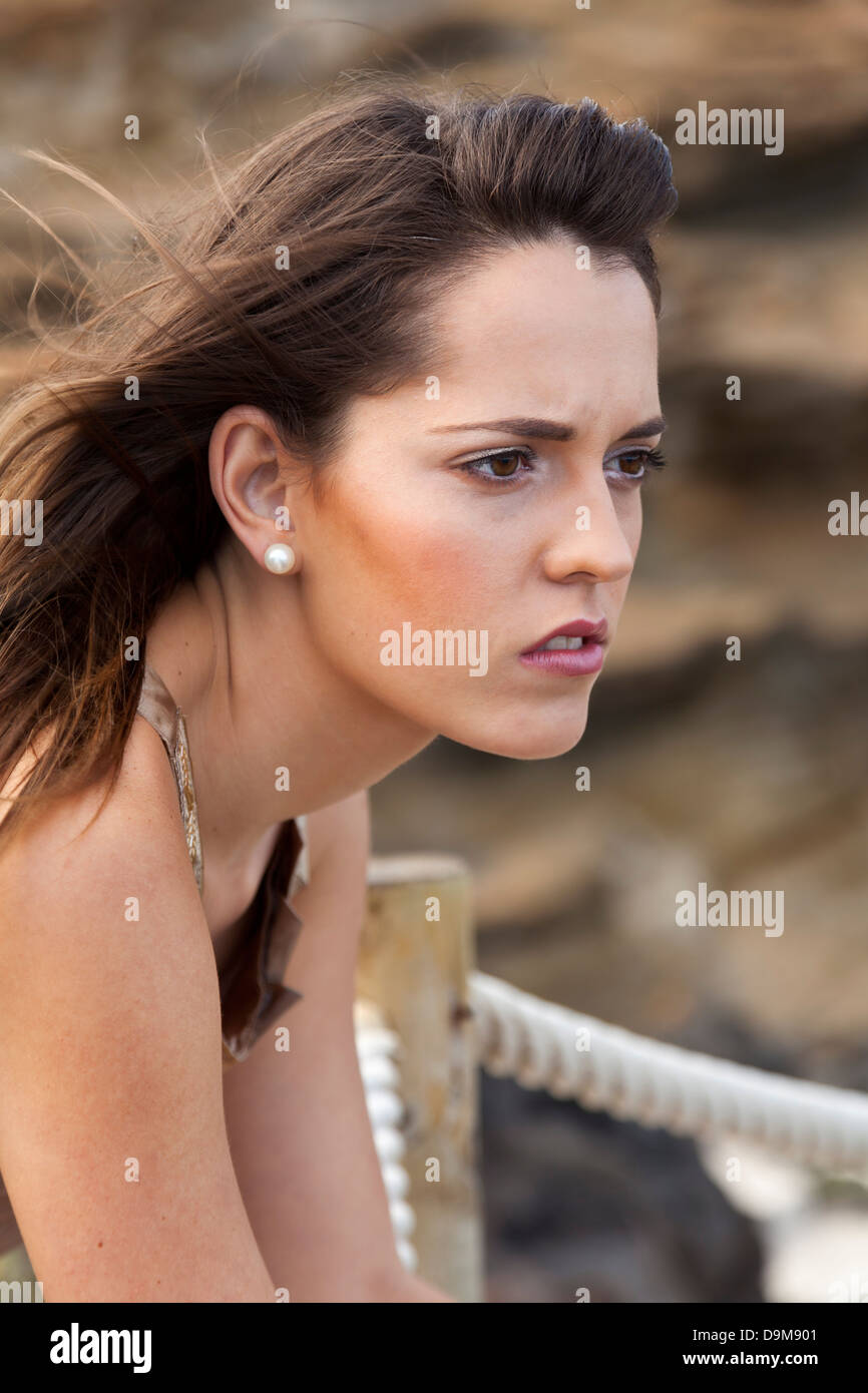 Pretty young woman leaning on rope fence looking concerned Stock Photo ...