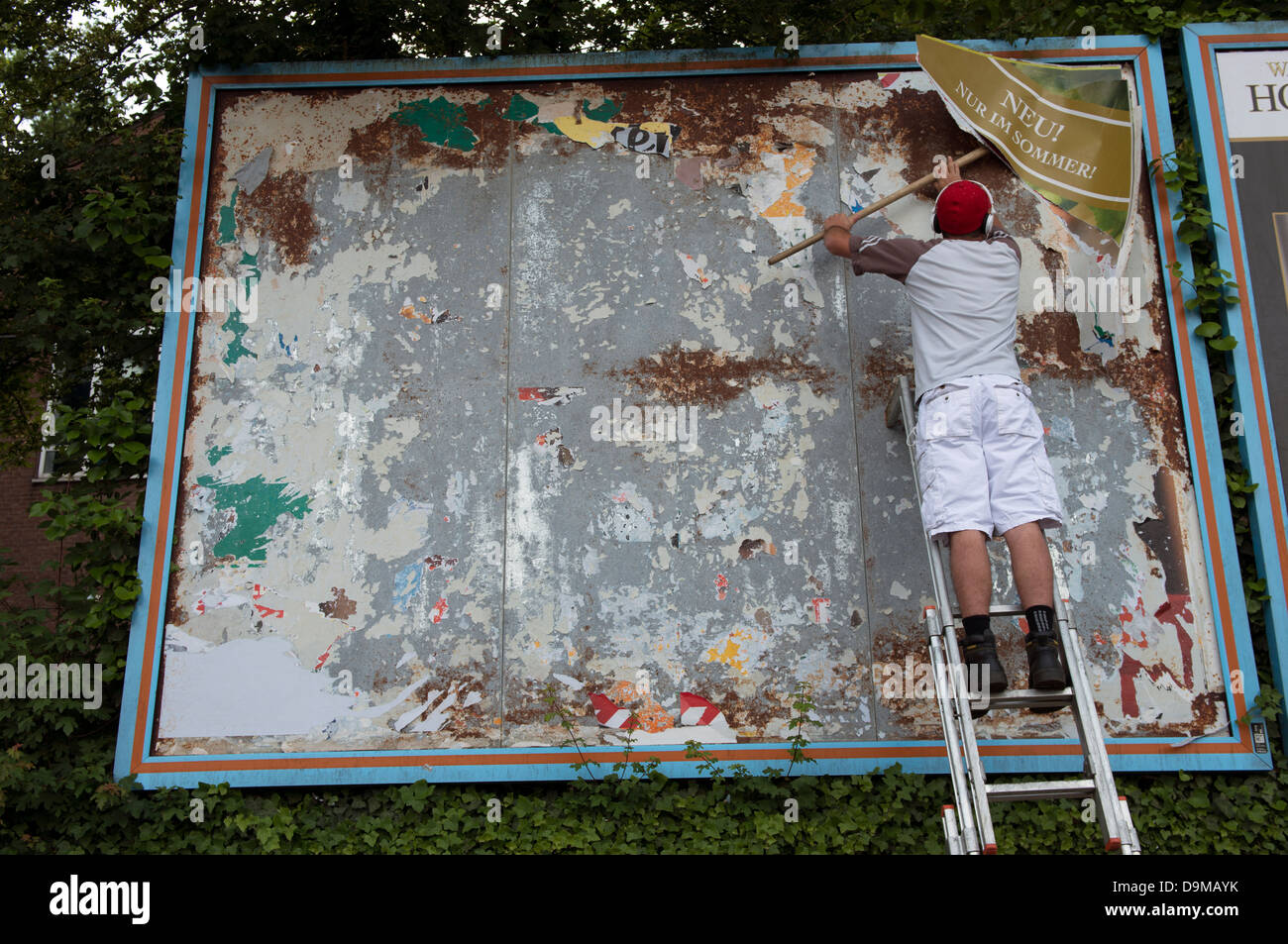 Worker cleaning away old billboard advertising Stock Photo - Alamy
