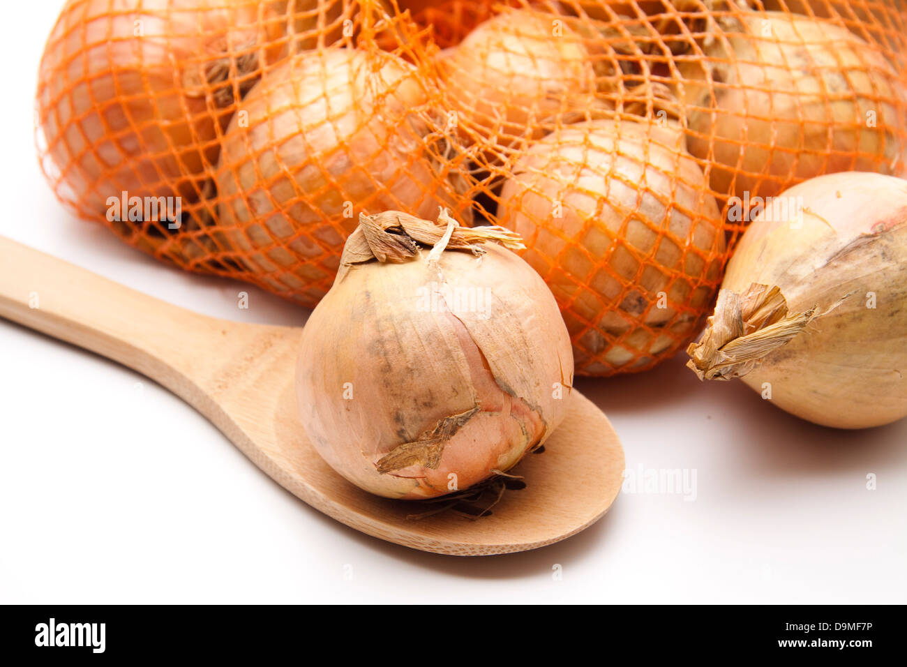 Onion on wooden spoon in the net Stock Photo - Alamy