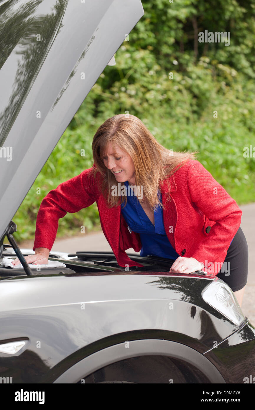 Female motorist with the bonnet up inspecting the engine department of ...