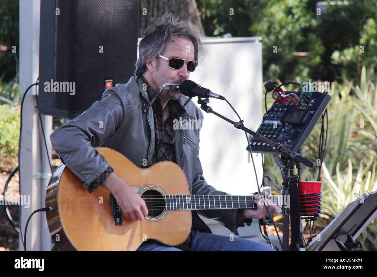 A man playing the harmonica and a guitar in a public presentation Stock ...