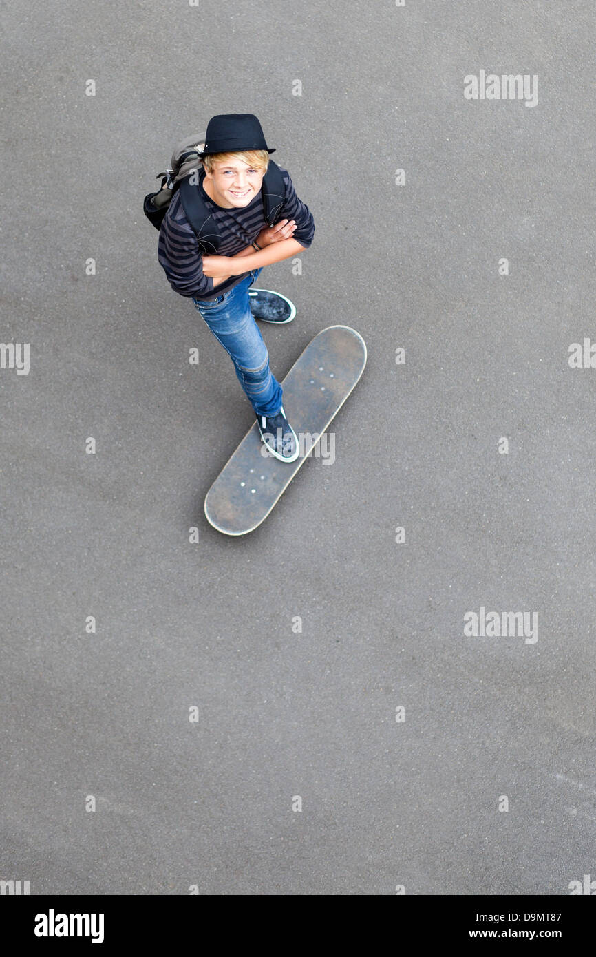 happy teen skateboarder standing on skateboard and looking up Stock ...