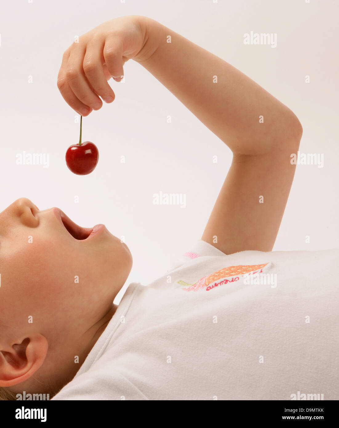 Young girl about to eat a cherry. Promoting healthy eating amongst the ...