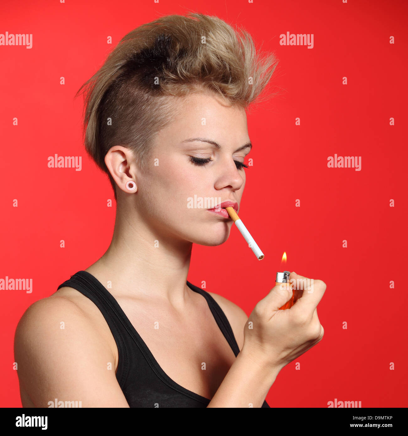 Fashion woman lighting a cigarette with a red background Stock Photo ...