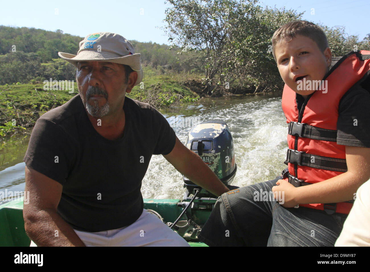A Cuban boatsman and his son travel in a boat on the river Yaguanabo in ...