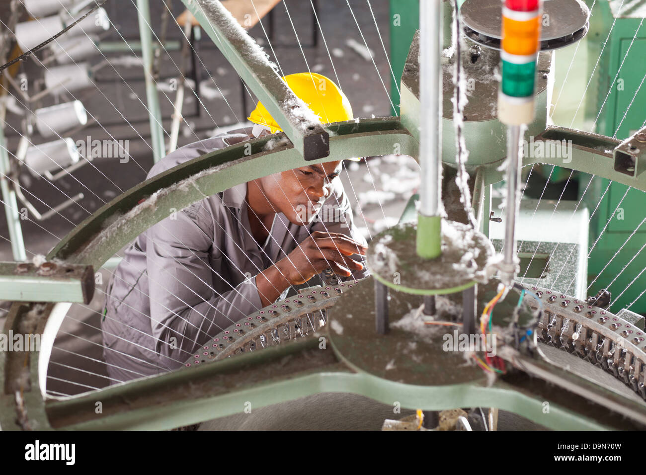 African American textile factory technician repairing weaving loom ...