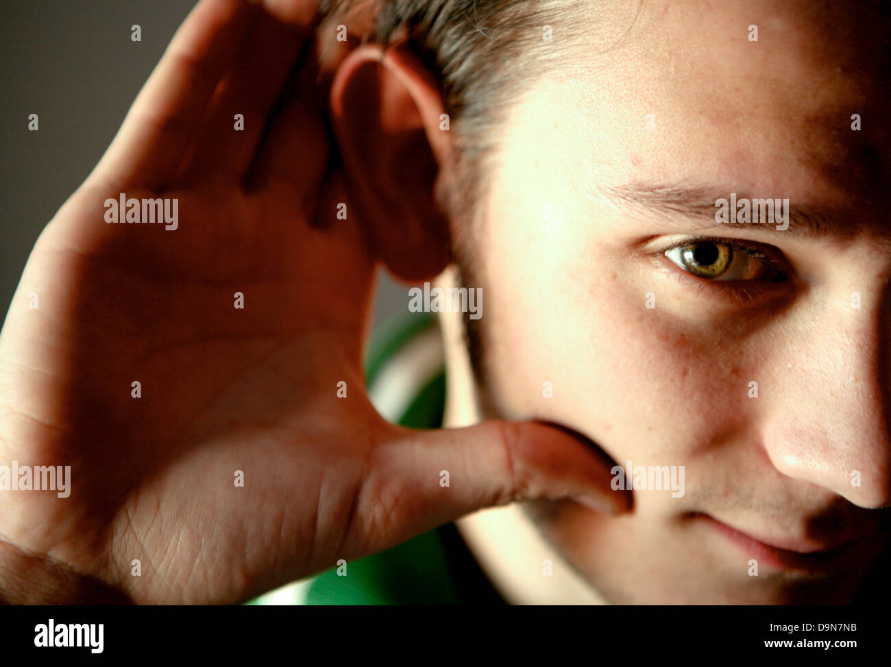 young man with hand to ear Stock Photo - Alamy