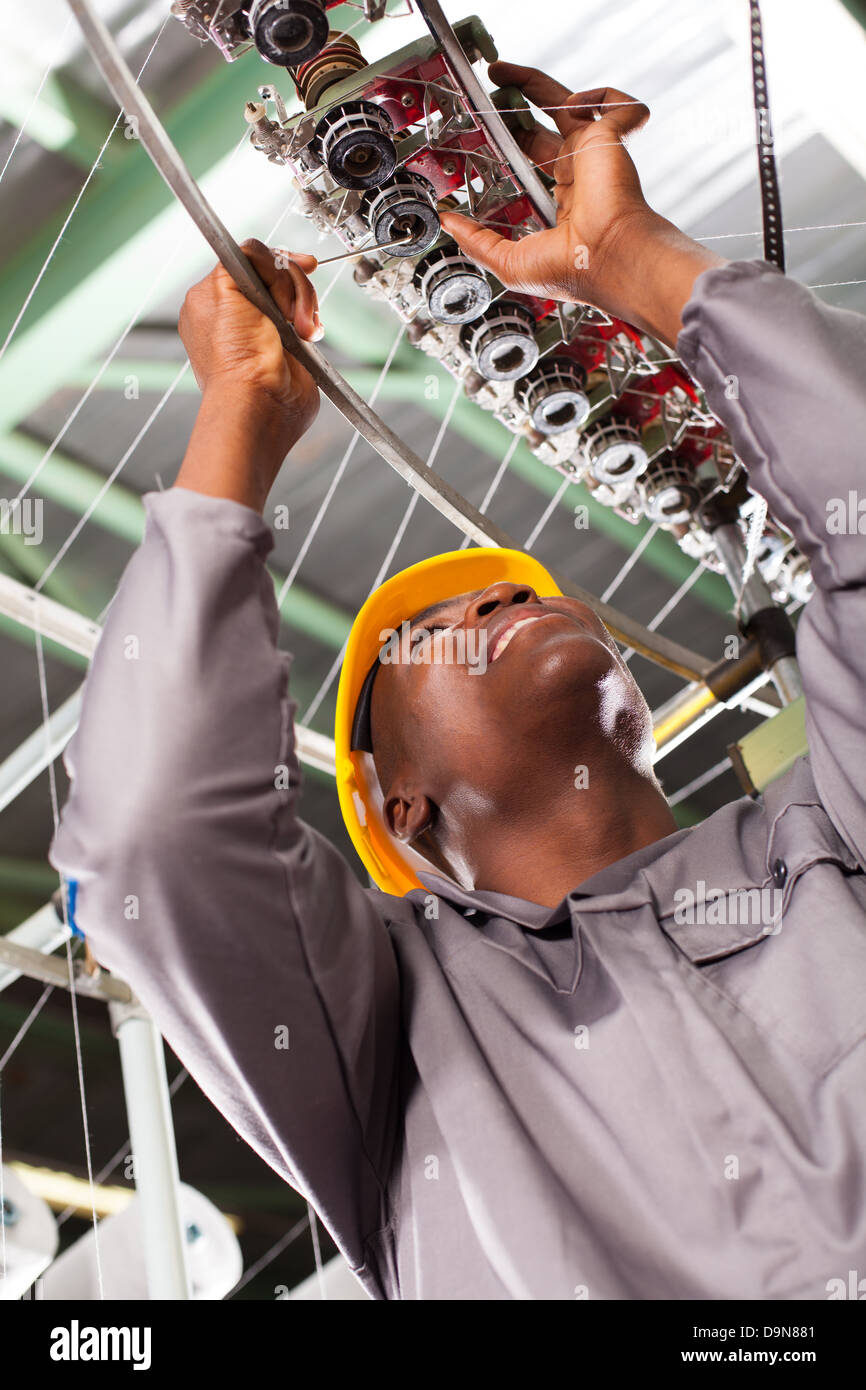 African American textile industrial technician repairing weaving ...