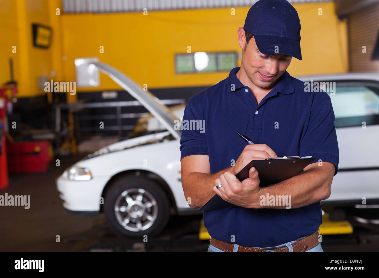 male auto workshop manager writing on clipboard at the repair shop ...