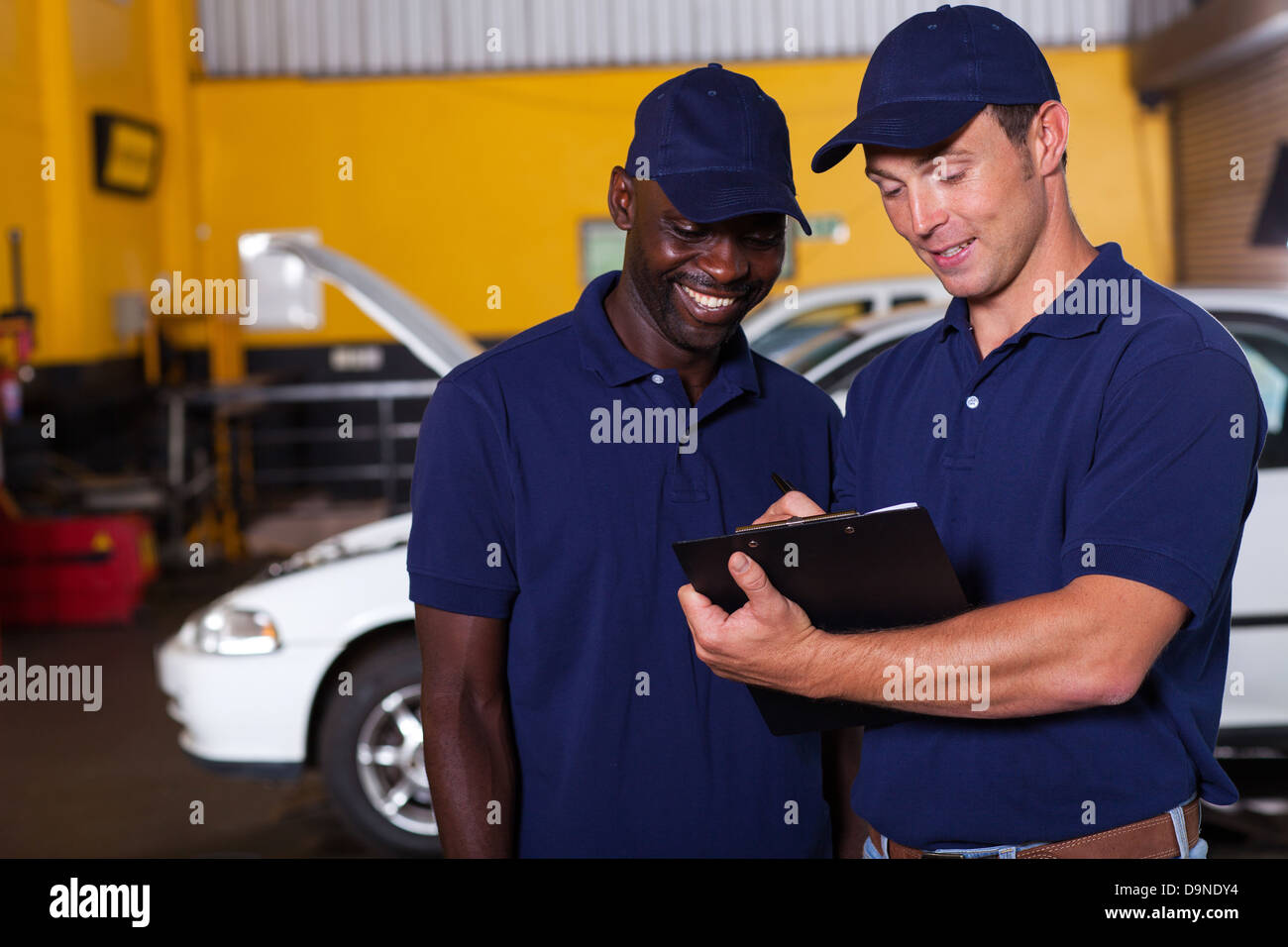 two happy auto mechanics going through checklist inside workshop Stock ...