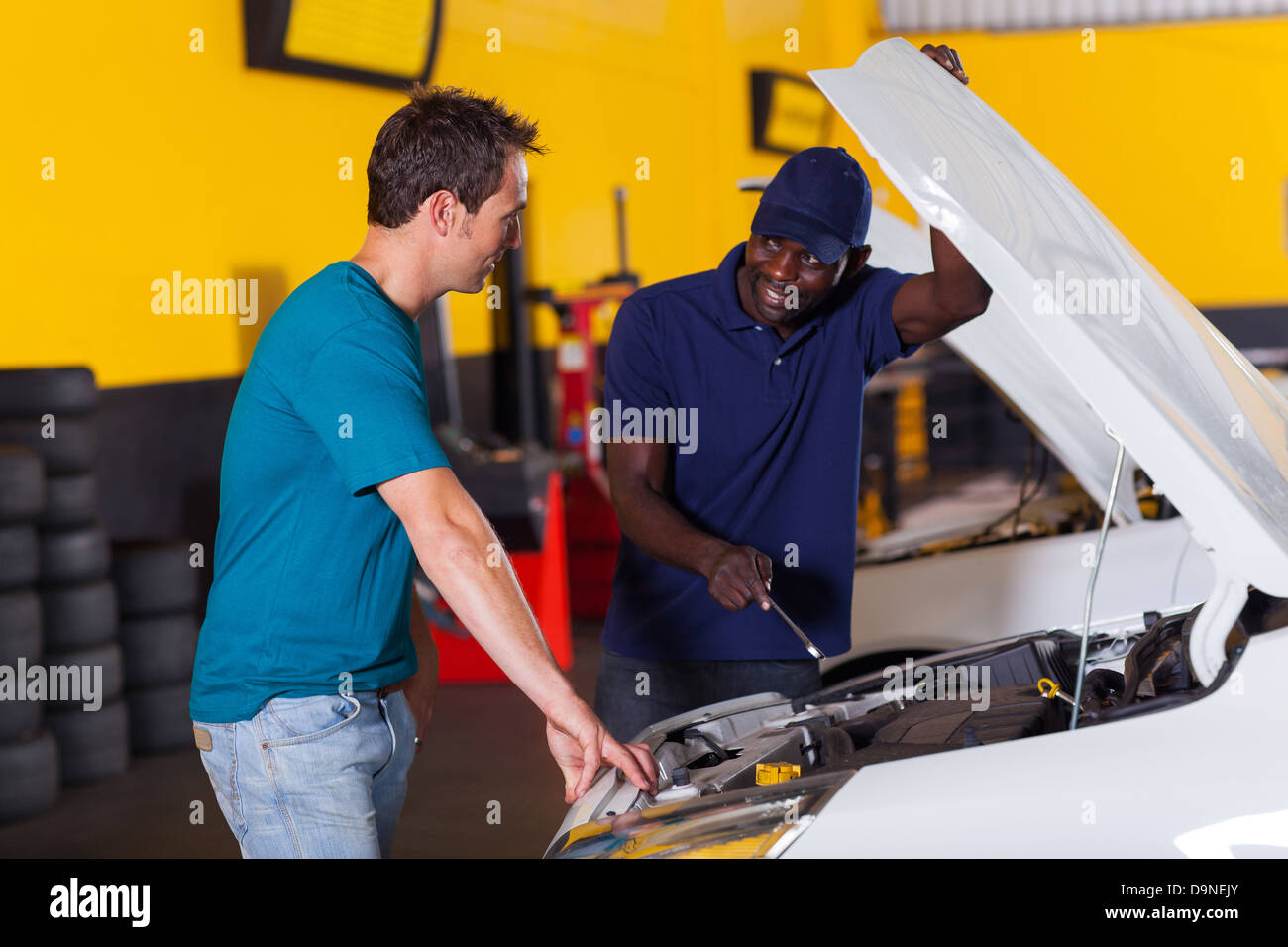 African auto mechanic and customer discussing vehicle fault Stock Photo ...