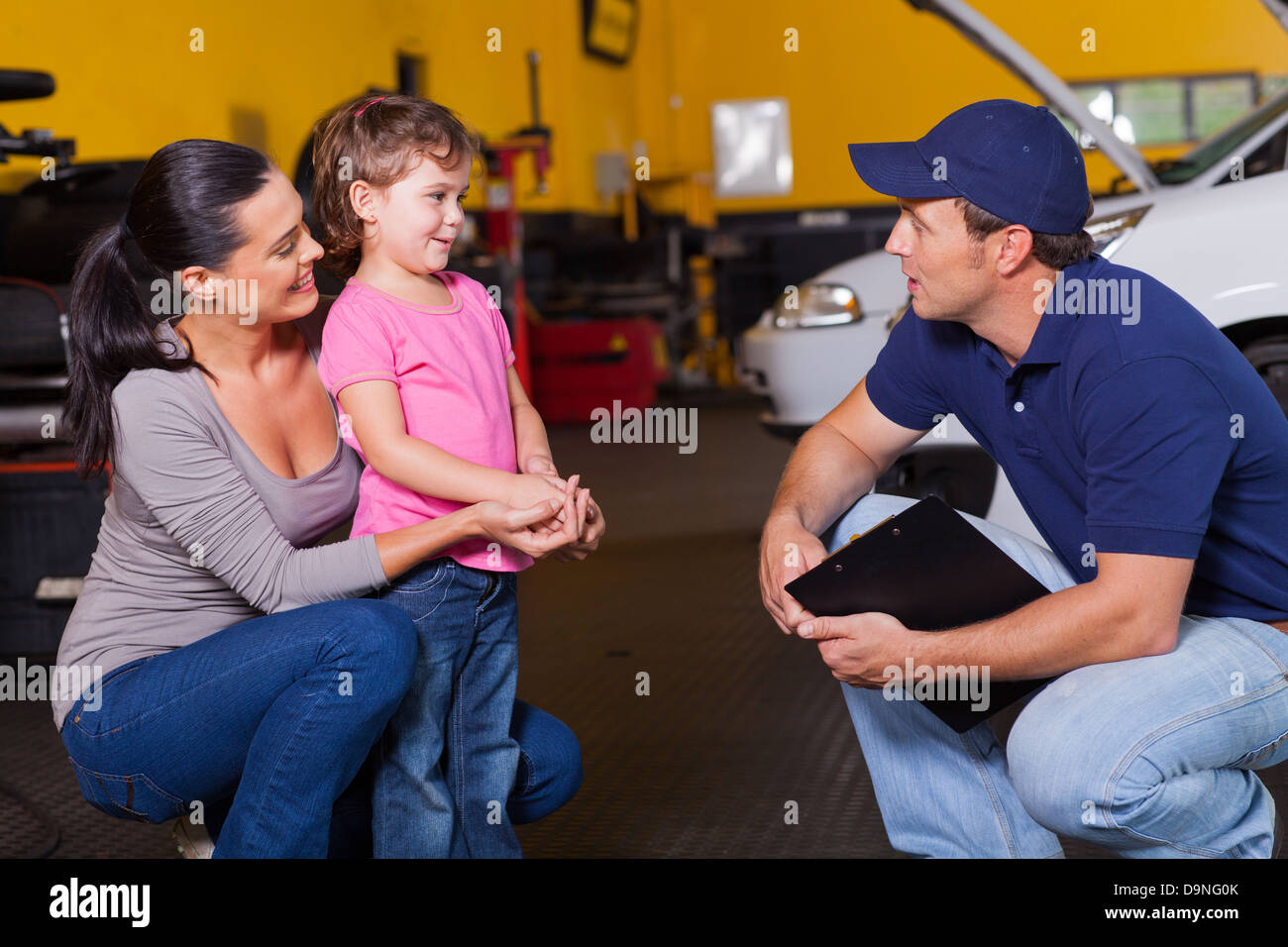 friendly auto technician talking to customer's little daughter in ...