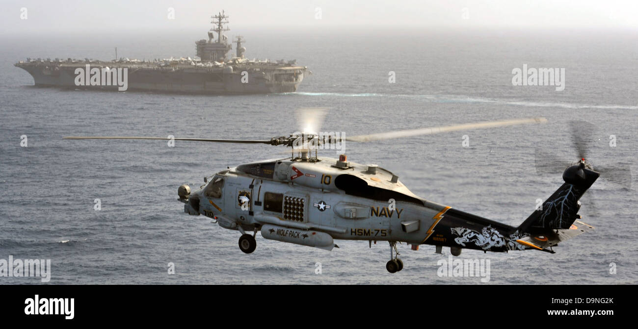 US Navy MH-60R Sea Hawk helicopters fly past the aircraft carrier USS ...