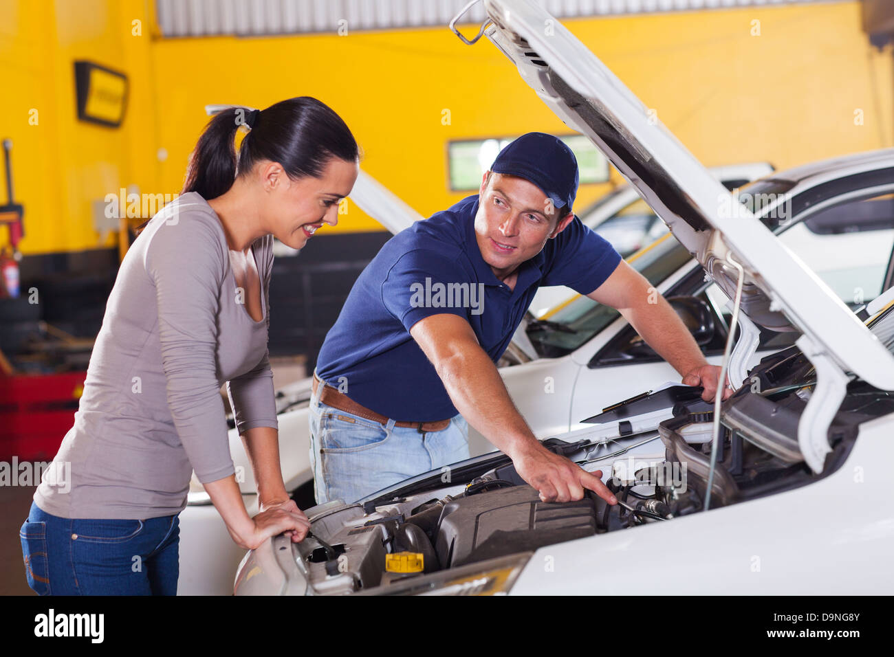 friendly mechanic showing female customer her car problem in garage ...