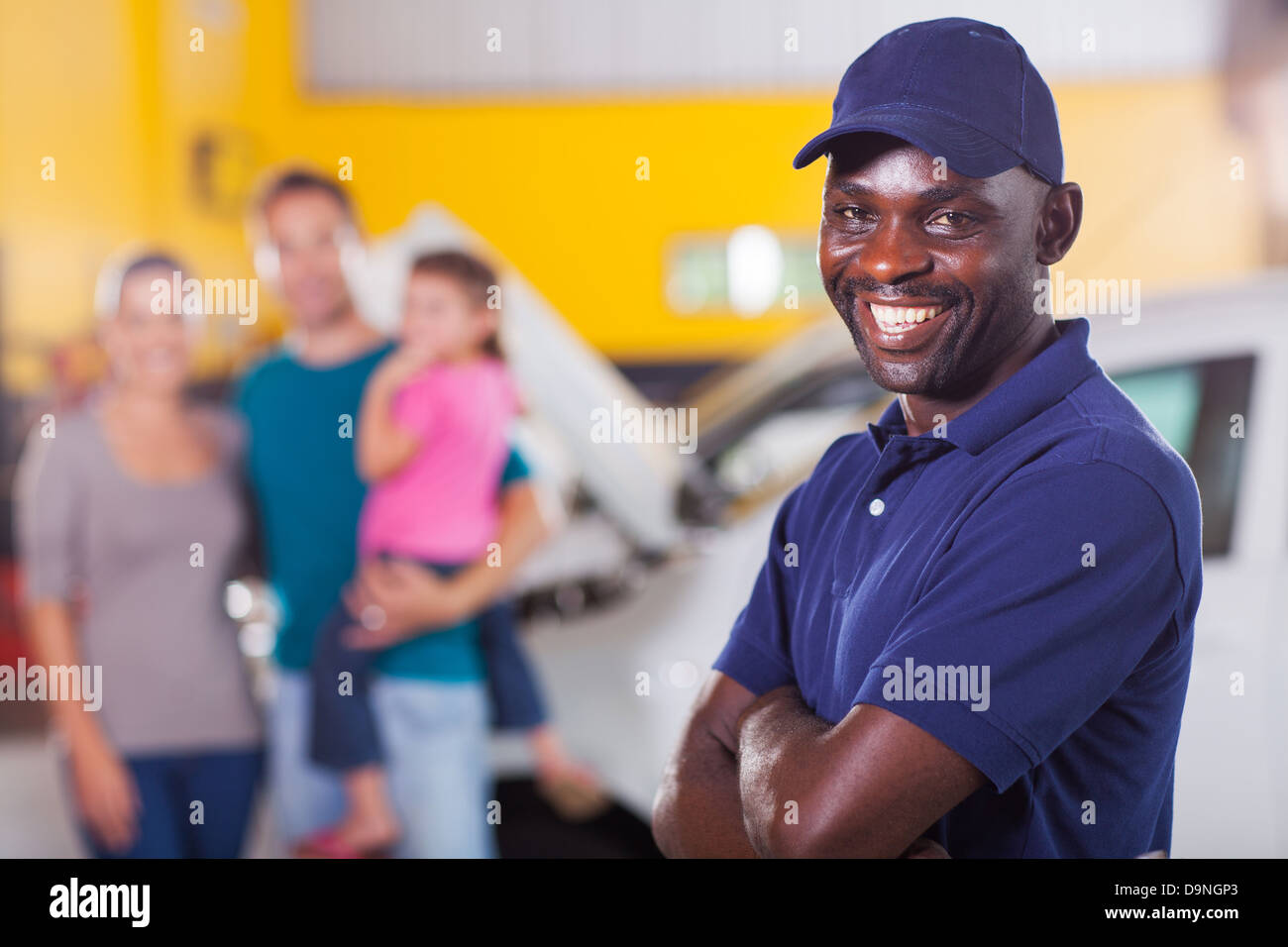 trustworthy African auto mechanic standing in front of family inside ...