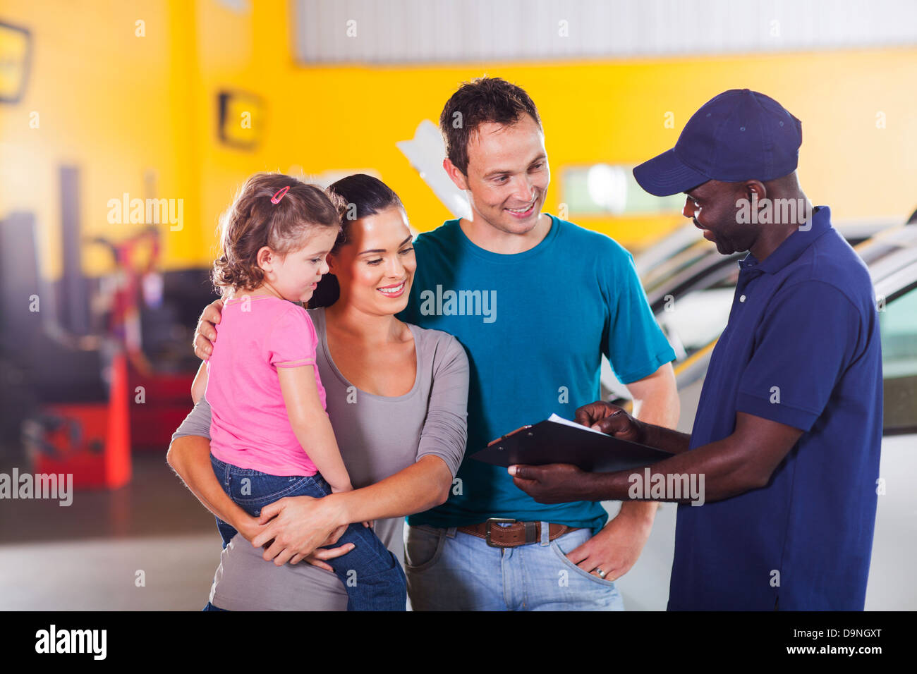 friendly auto mechanic talking to young family in garage Stock Photo ...