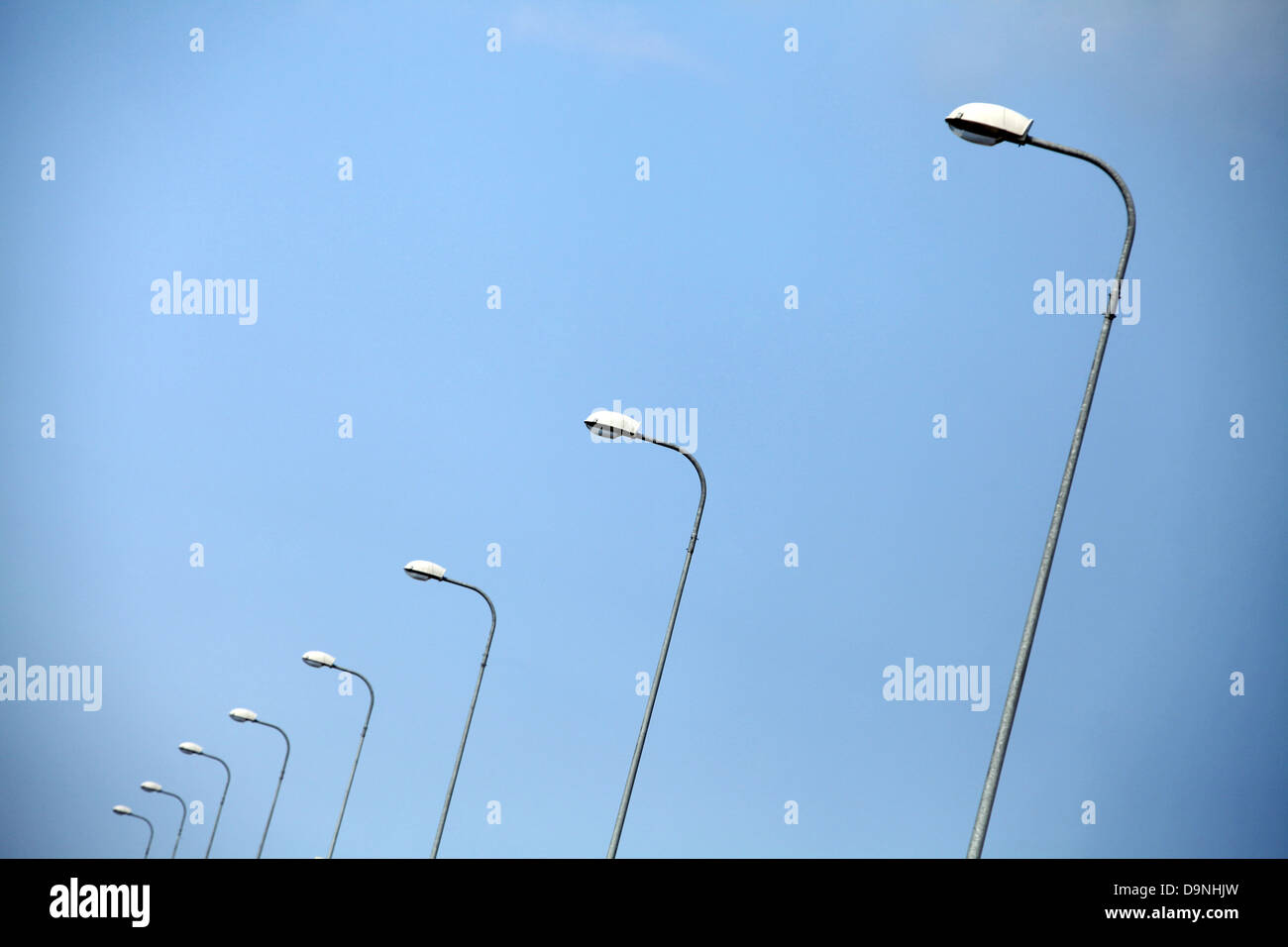 A line of light poles on a blue sky Stock Photo - Alamy