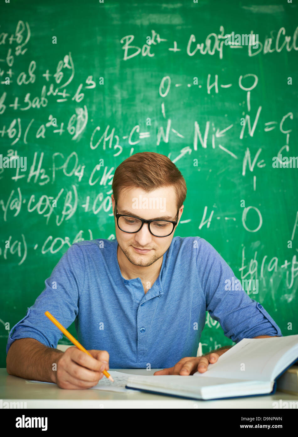 Portrait of handsome student carrying out graduation test on background ...