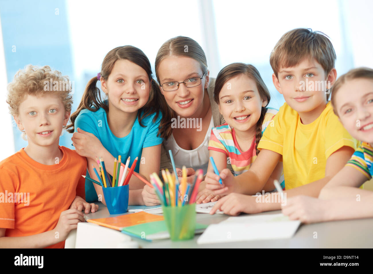Portrait of diligent schoolkids and successful teacher looking at ...