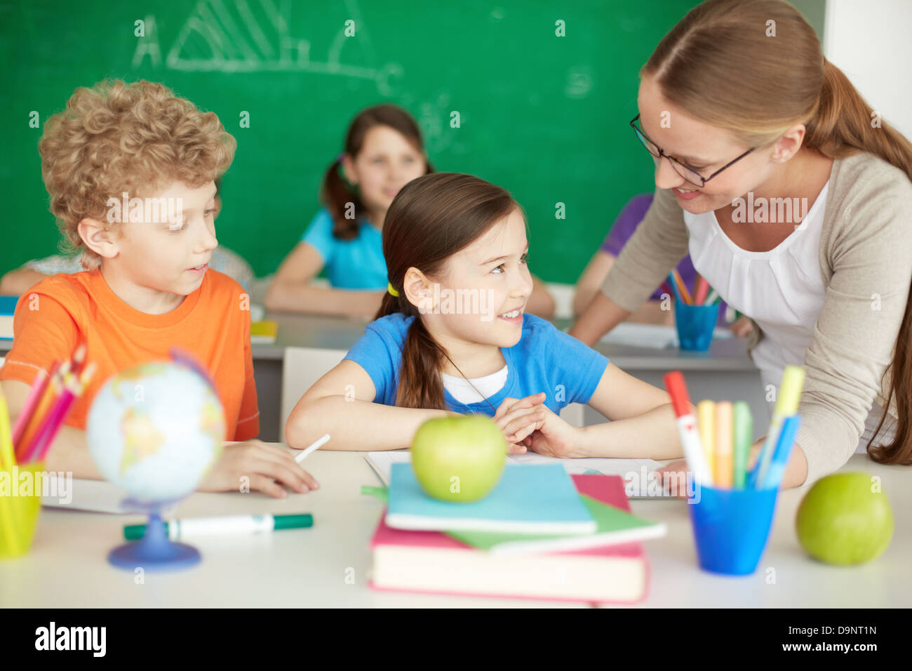 Portrait of diligent schoolkids and teacher interacting at lesson Stock ...