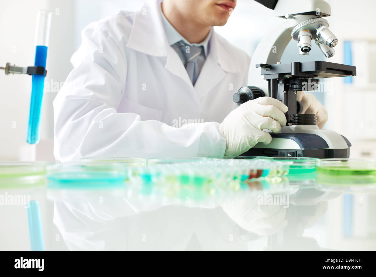 Young clinician looking into microscope in laboratory Stock Photo - Alamy