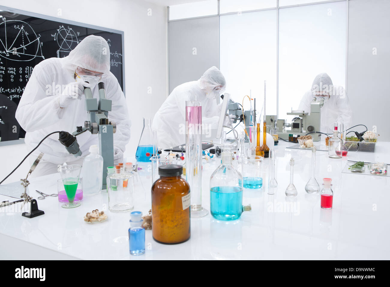 general-view of three people observing and analysig chemical reactions ...