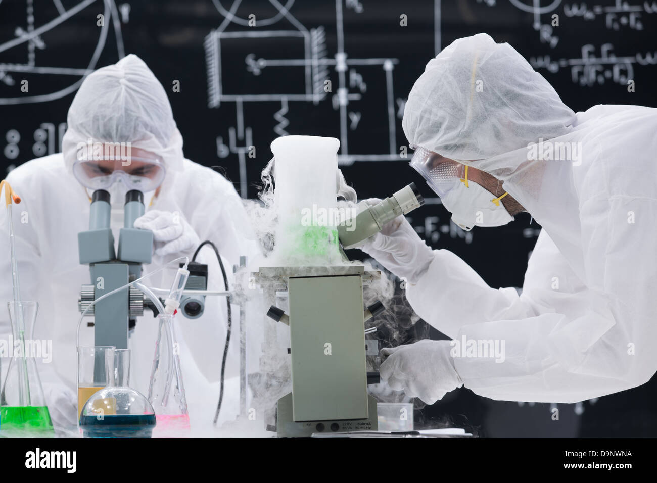 close-up of two scientists analyzing under microscope in a chemistry ...