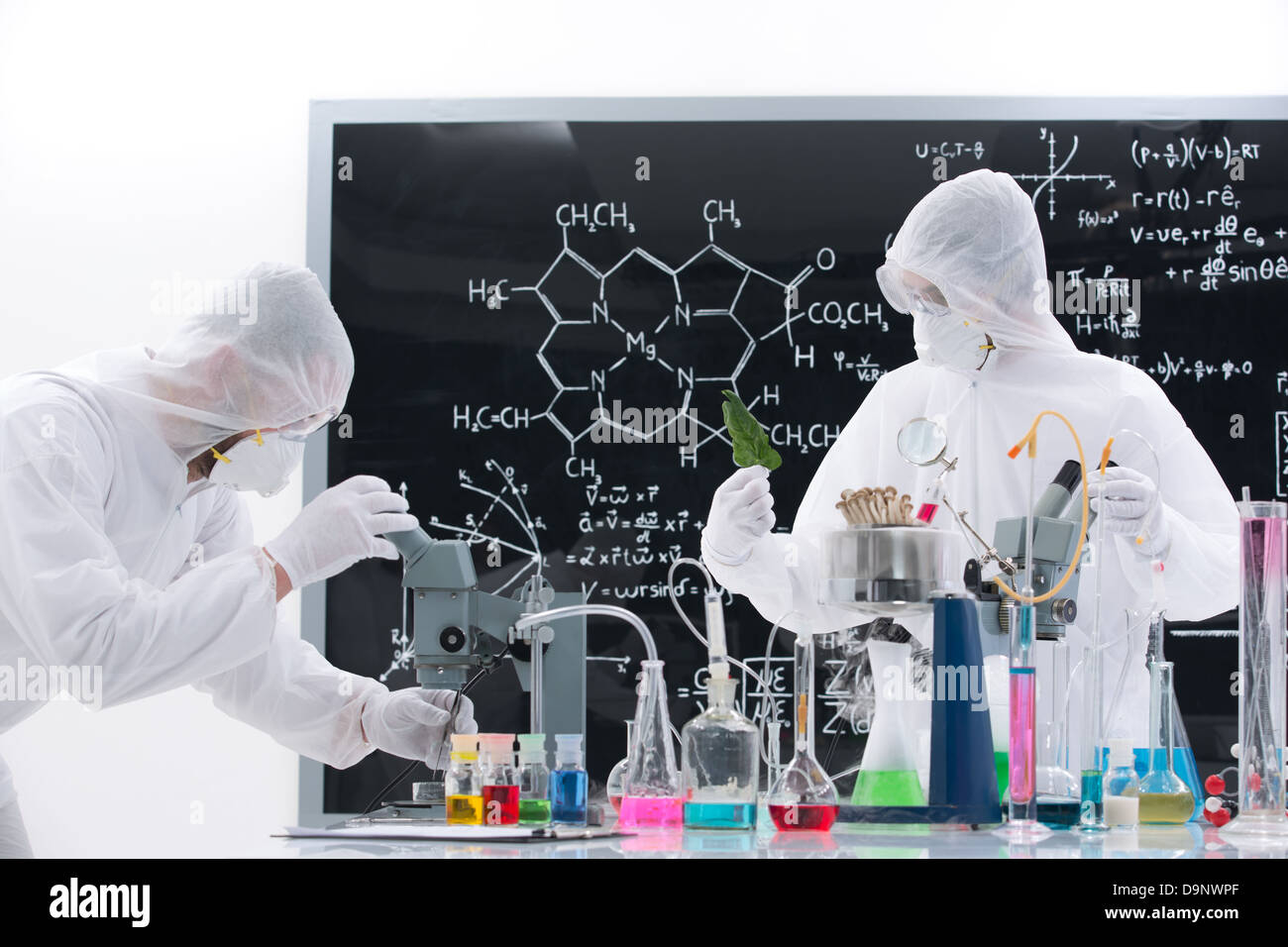 side-view of two people manipulating lab tools and colorful liquids on ...