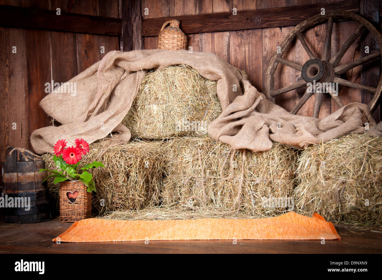 Interior of a rural farm - hay, wheel, flower Stock Photo - Alamy