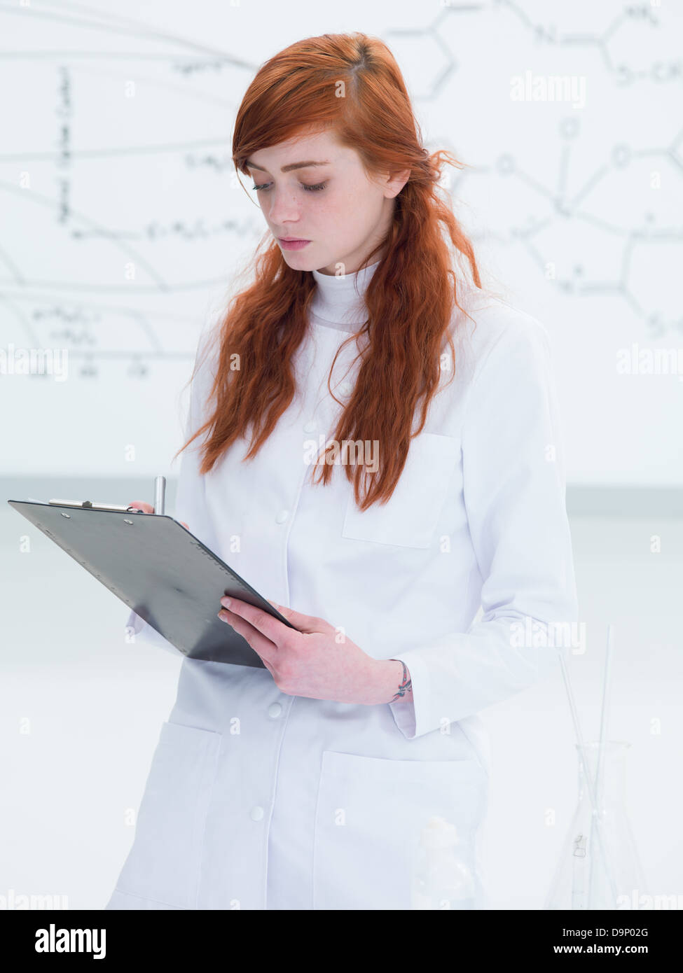 side-view of a student in a chemistry lab taking notes on a clip-board ...