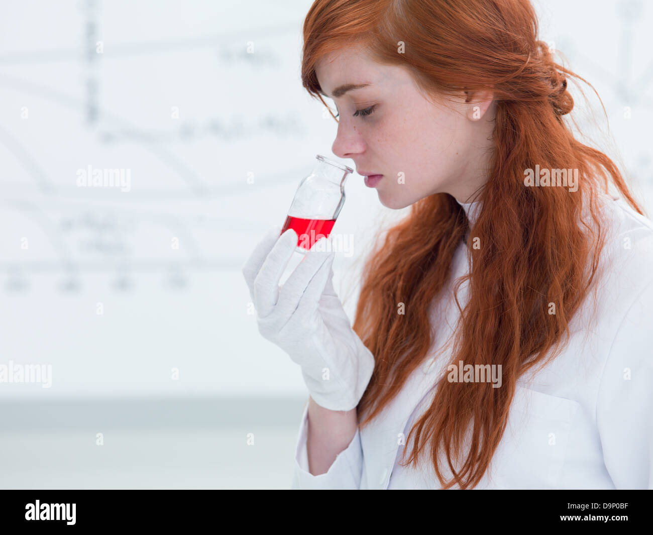 close-up of a pretty student in a chemistry lab smelling colorful ...