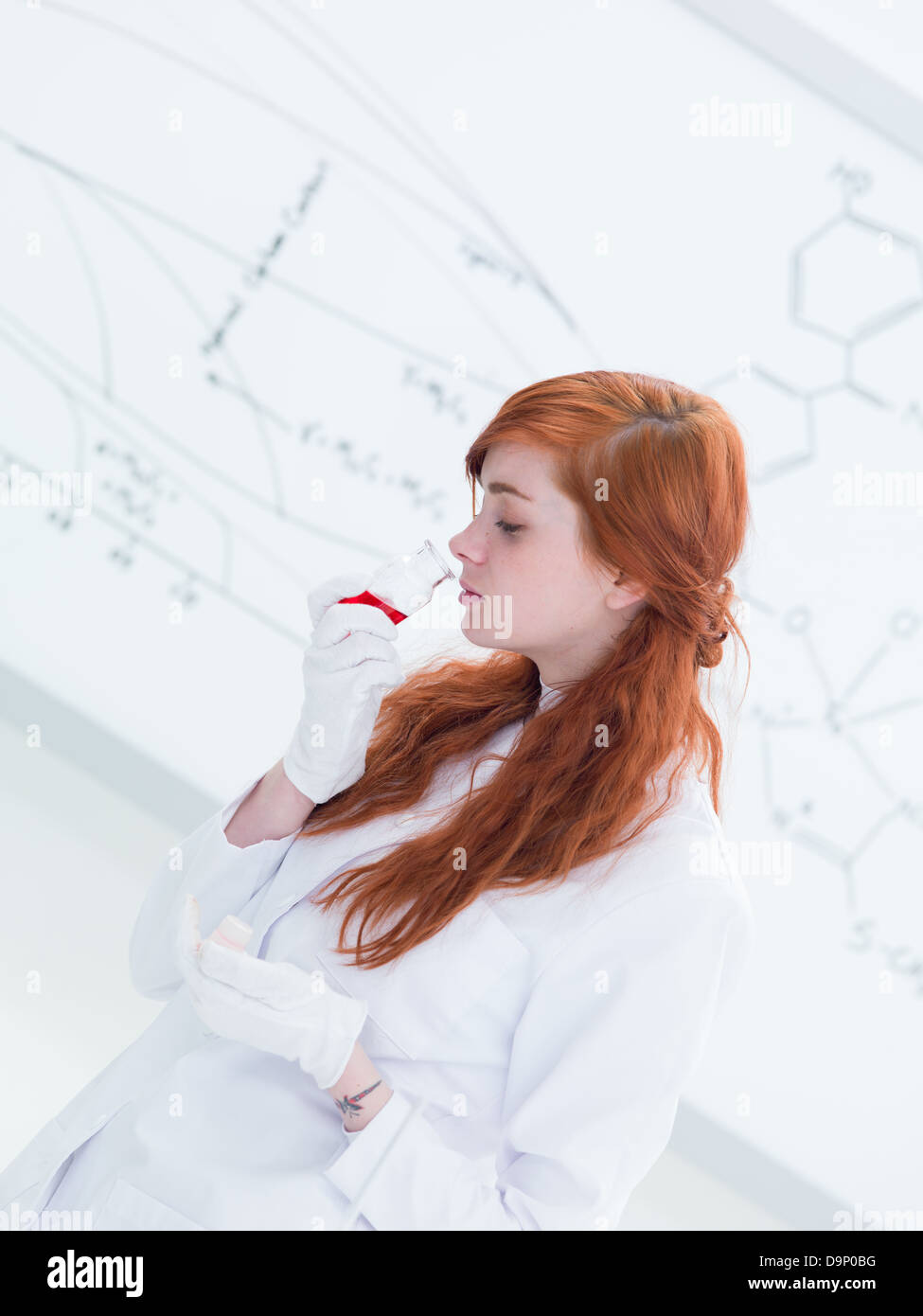side-view of a pretty student in a chemistry lab smelling colorful ...