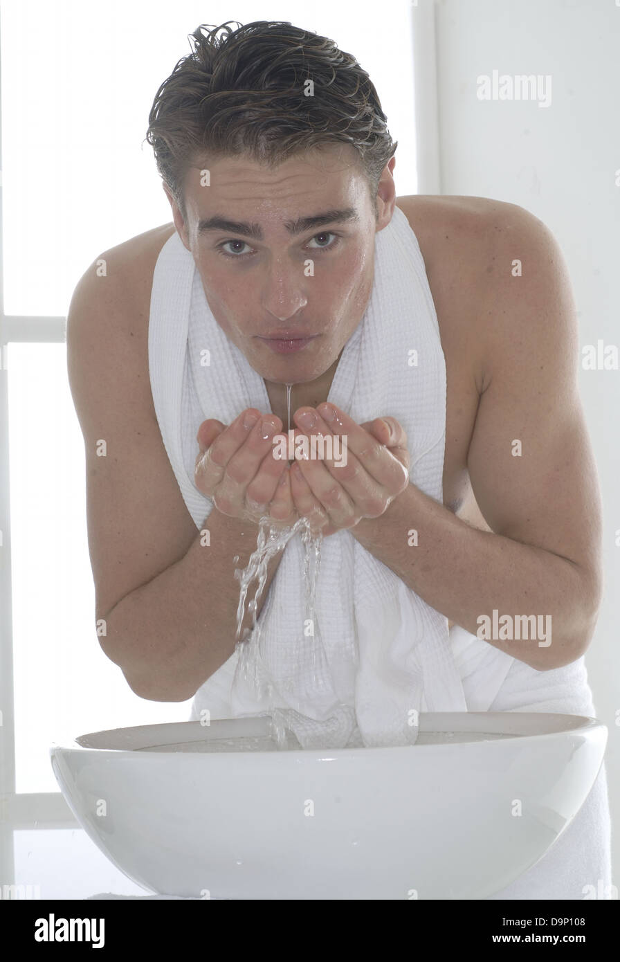 Man standing in front of a washbowl washing his face Stock Photo - Alamy