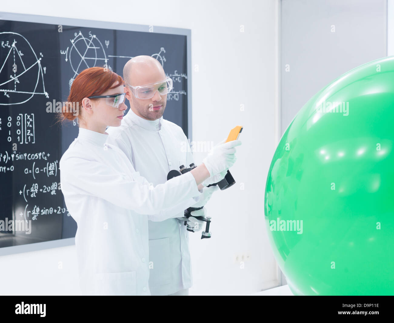 side view of teacher and student in a chemistry lab scanning a green ...