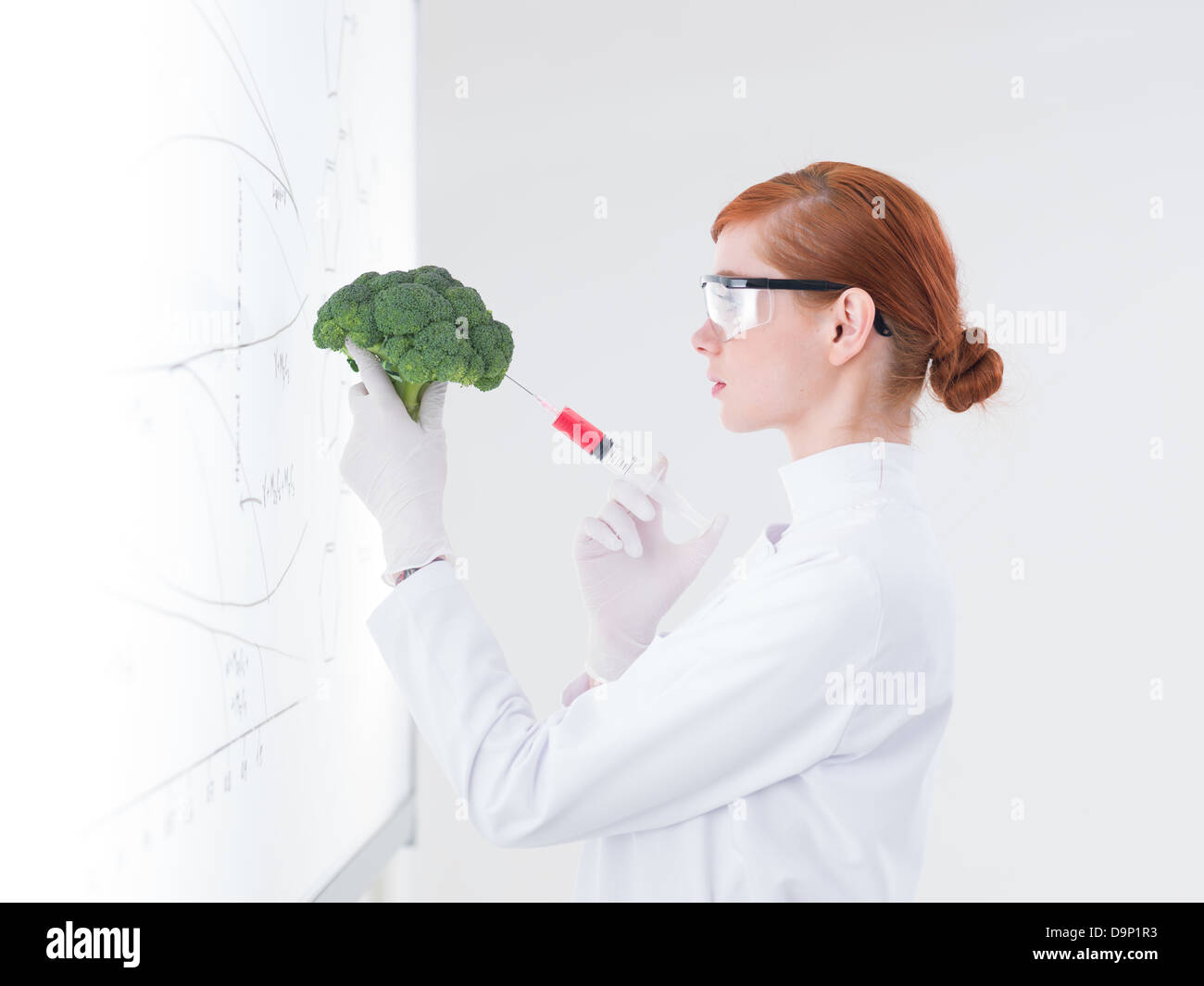 side-view of one beautiful student injecting a broccoli in front of a ...