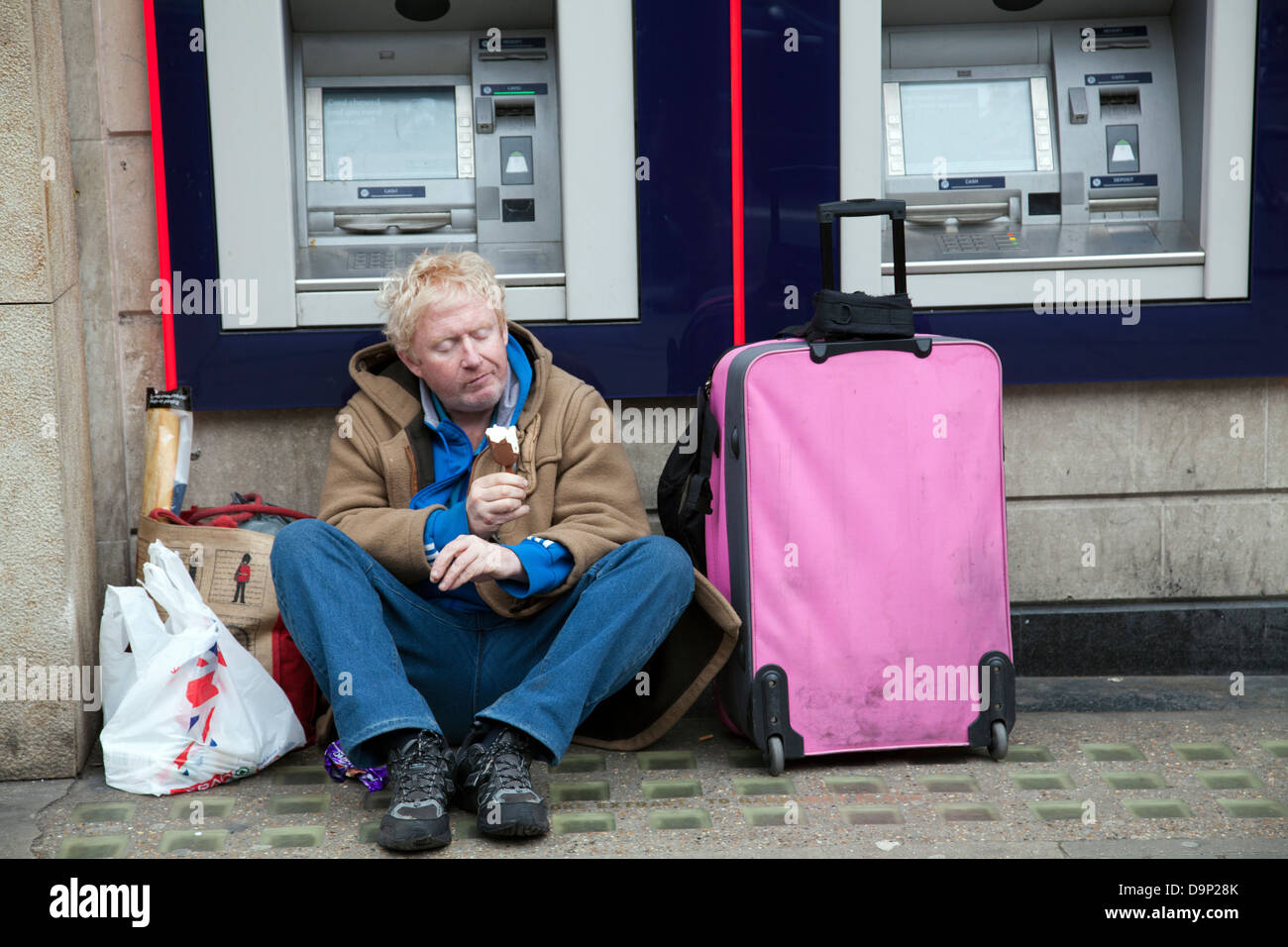 Homeless man with belongings eating Ice Cream in front of Natwest ATM ...