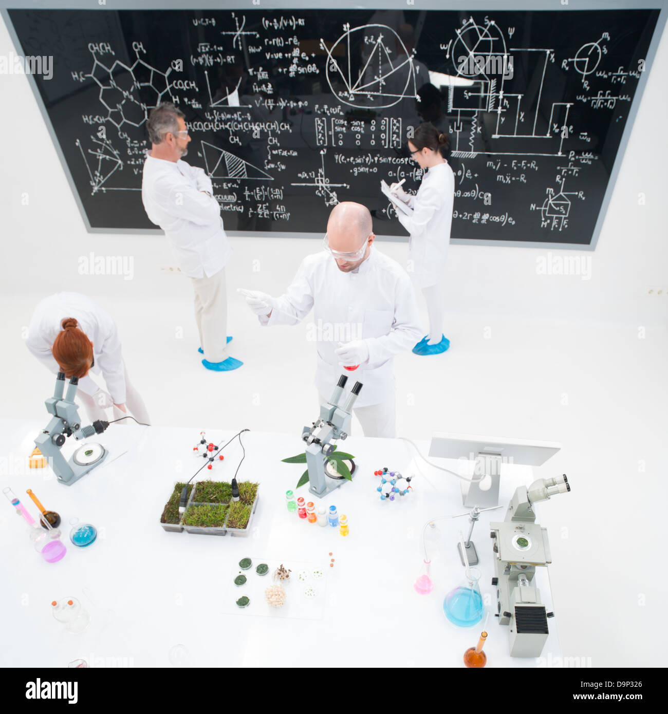 bird-eye of four people in a chemistry lab conducting experiments ...