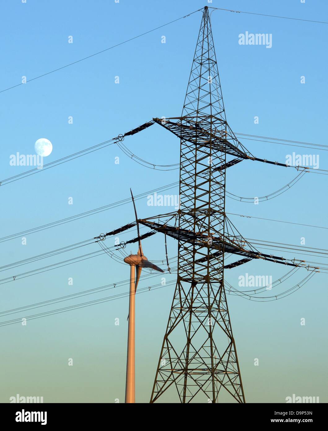 Wind turbines, pylons, and power lines are pictured in the evening ...