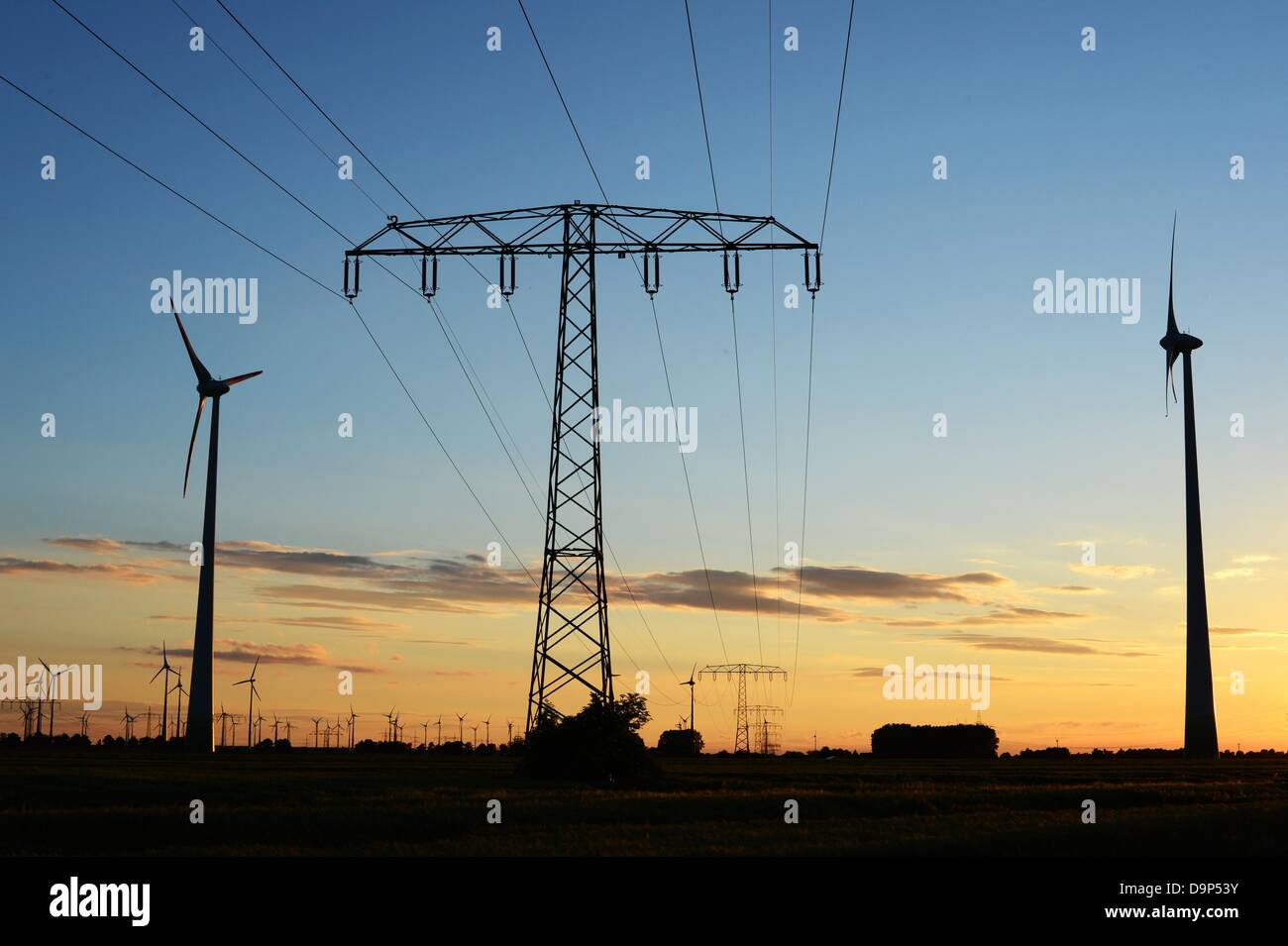 Wind turbines, pylons, and power lines are pictured in the evening ...