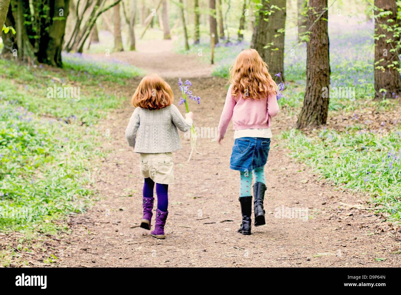 Two little girls walking through bluebell woods Stock Photo - Alamy