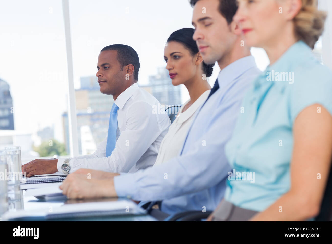 Colleagues sitting in line Stock Photo - Alamy