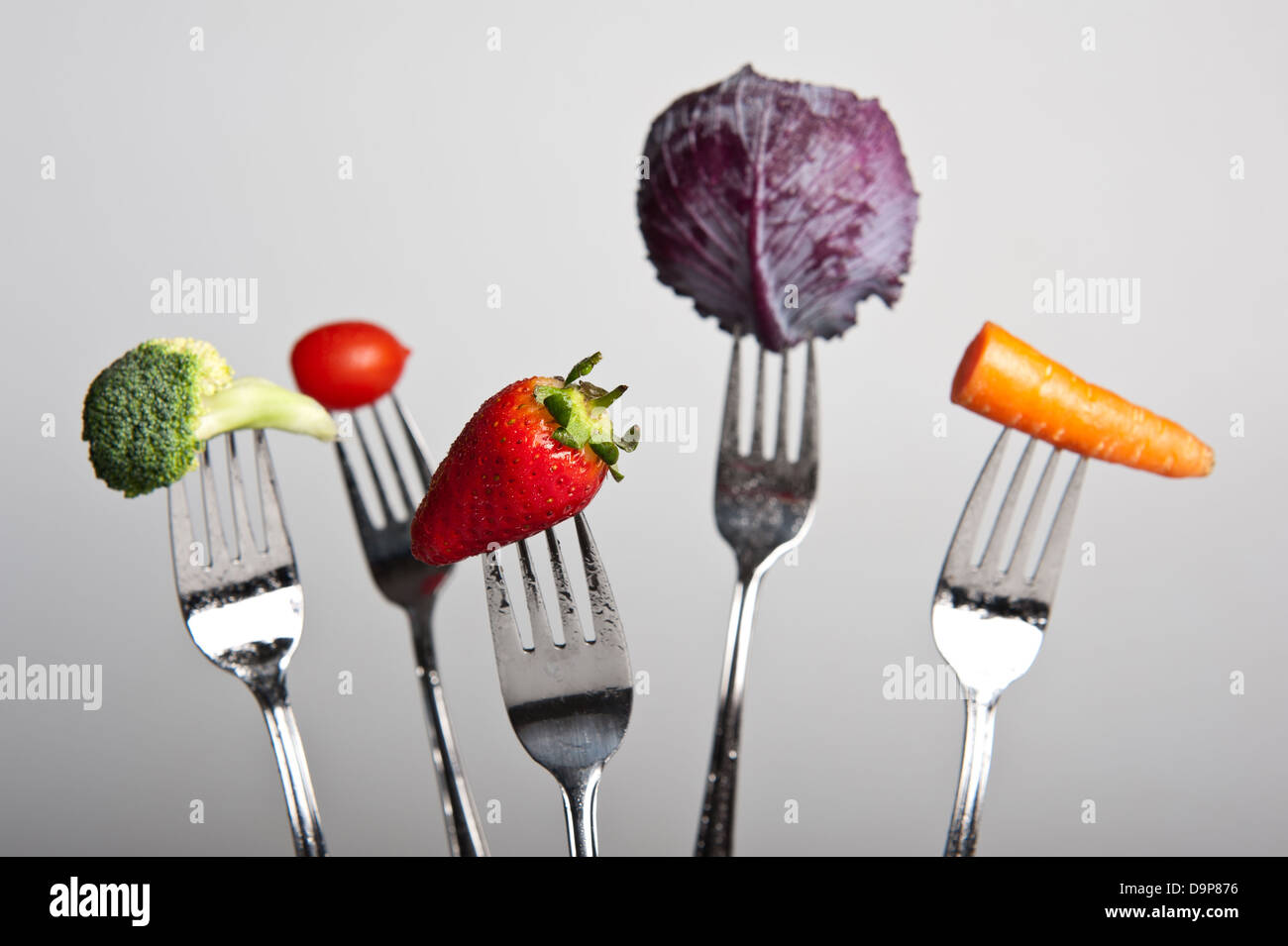 5 forks in soil each containing some vegetable or fruit with tiny water ...