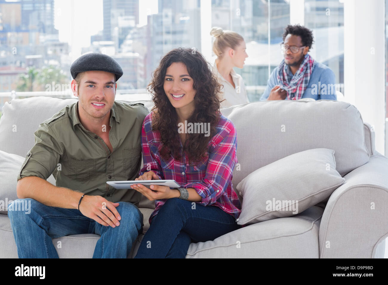 Employees working on a tablet computer on a couch Stock Photo - Alamy
