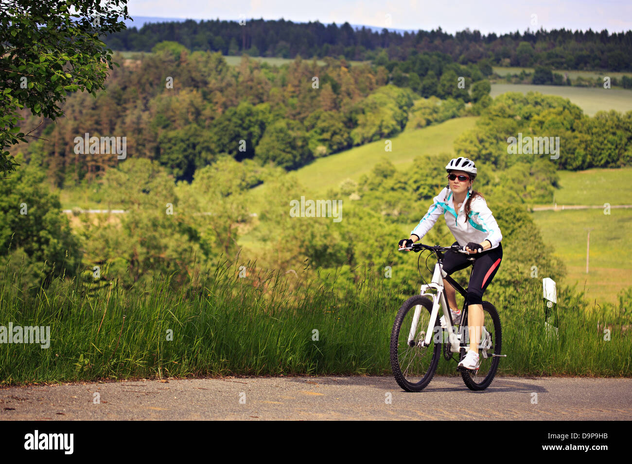 A cycling woman in front of rural landscape Stock Photo - Alamy